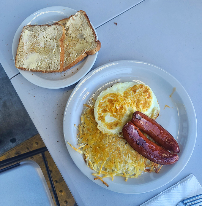 The holy trinity of breakfast: golden hash browns, Portuguese sausage with that perfect snap, and eggs sunny-side up. Morning salvation on a plate.