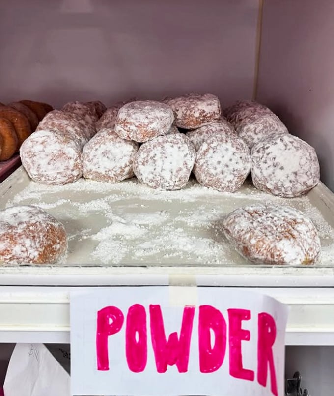 Powdered donuts stacked like snowy mountains, each one a potential avalanche of sugar waiting to dust your shirt. Totally worth the mess.