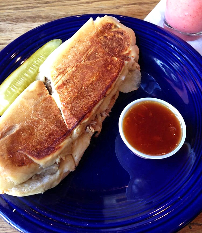 The pressed duck sandwich that launched a thousand return visits, served with a pickle that knows its supporting role.