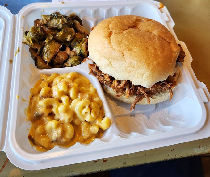 The pulled pork sandwich: where tender smoked meat meets pillowy bun, with mac and cheese and Brussels sprouts playing perfect supporting roles.