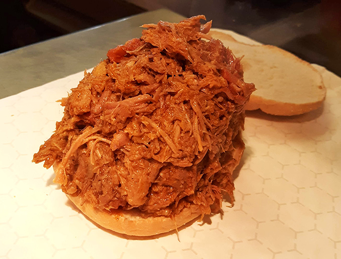 A mountain of pulled pork waiting for its close-up. This isn't just a sandwich&mdash;it's a commitment to excellence and possibly a nap afterward.