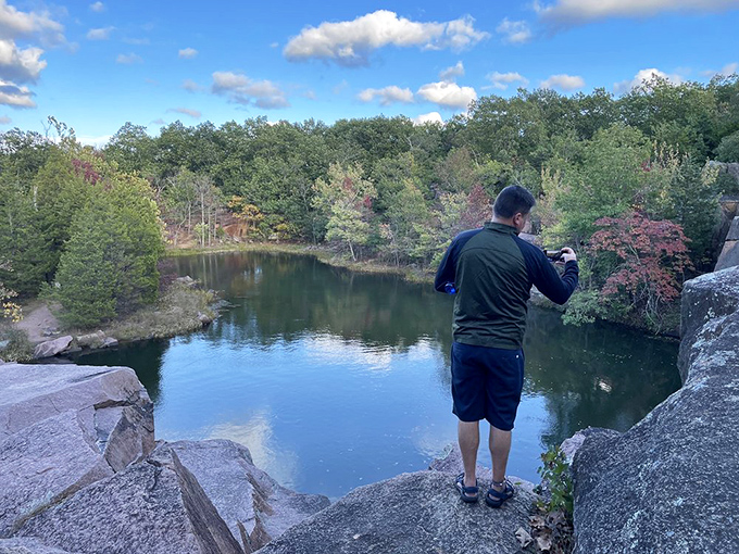 A photographer captures the serene quarry pond. Once a site of industrial activity, nature has reclaimed it with breathtaking beauty.