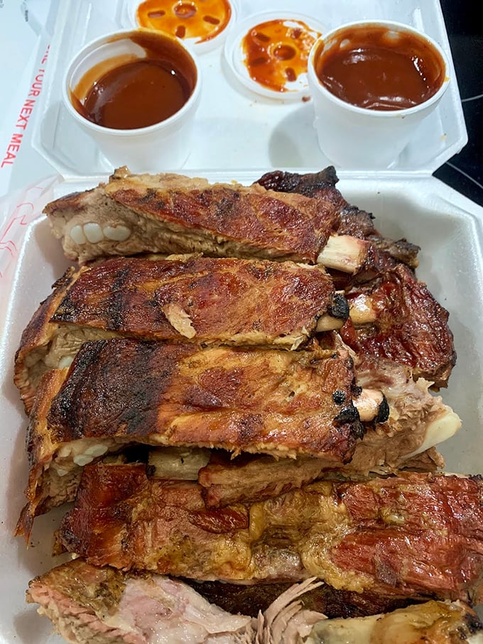 Ribs with sauce cups standing by, though they hardly need the help. That bark speaks volumes about patience and fire management.