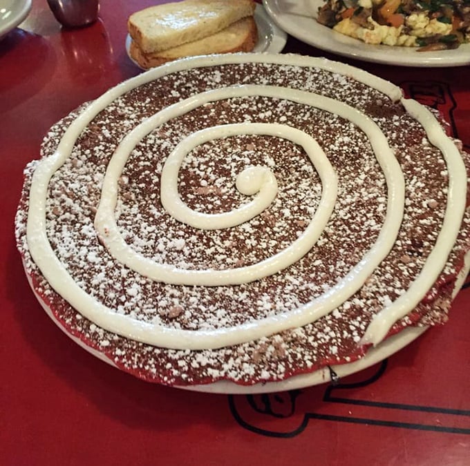 The Red Velvet pancake arrives with hypnotic swirls of cream cheese icing, like a dessert that successfully infiltrated breakfast.