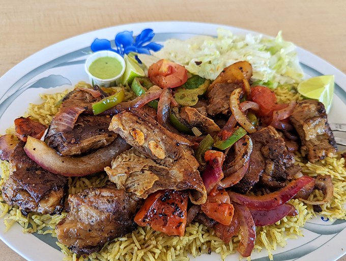 The legendary roasted goat cutlet arrives on a bed of golden rice, surrounded by vegetables that know their supporting role in this meaty masterpiece.
