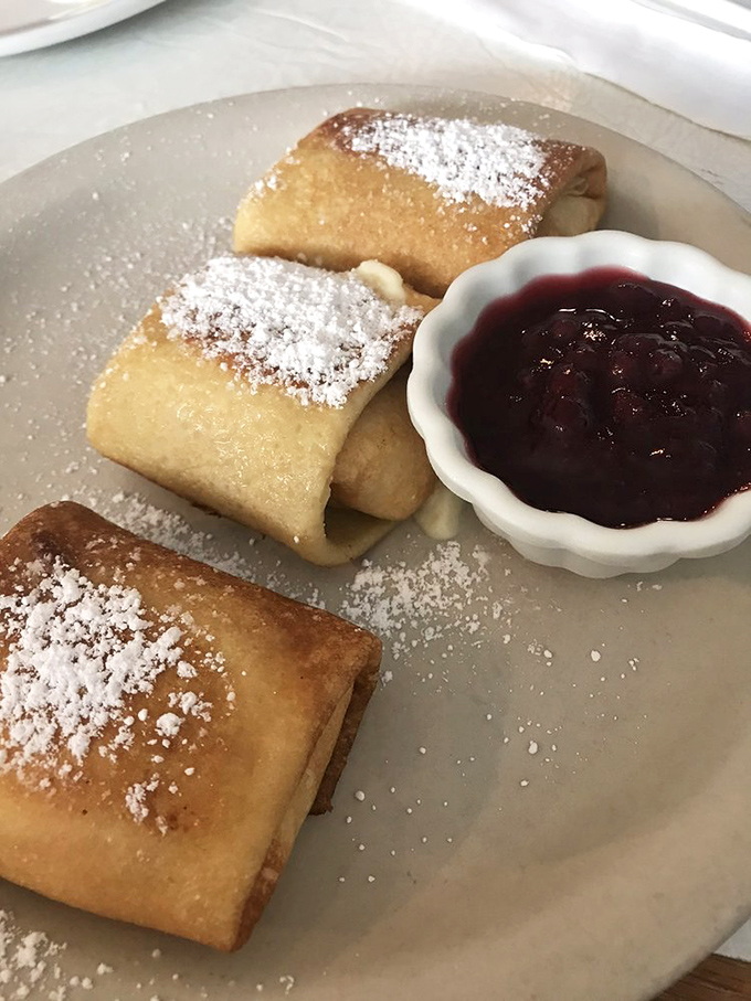 Russian Blintzes dusted with powdered sugar and served with berry compote&mdash;like delicate envelopes delivering sweet messages directly to your taste buds.