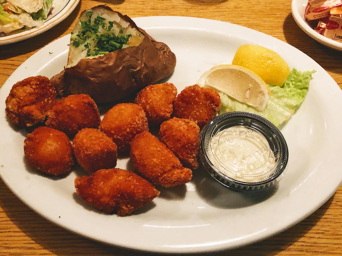 Golden-fried scallops that crunch then melt, like ocean-flavored clouds wearing crispy jackets. The baked potato stands by, reliable as an old friend.