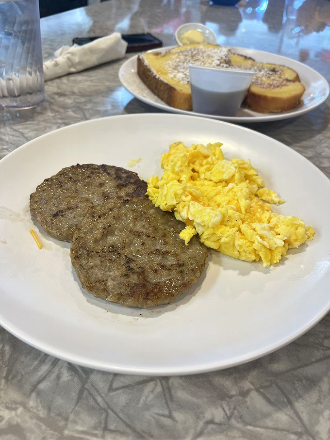 Simple pleasures done right: perfectly scrambled eggs alongside sausage patties. Sometimes breakfast doesn't need to be complicated to be extraordinary.