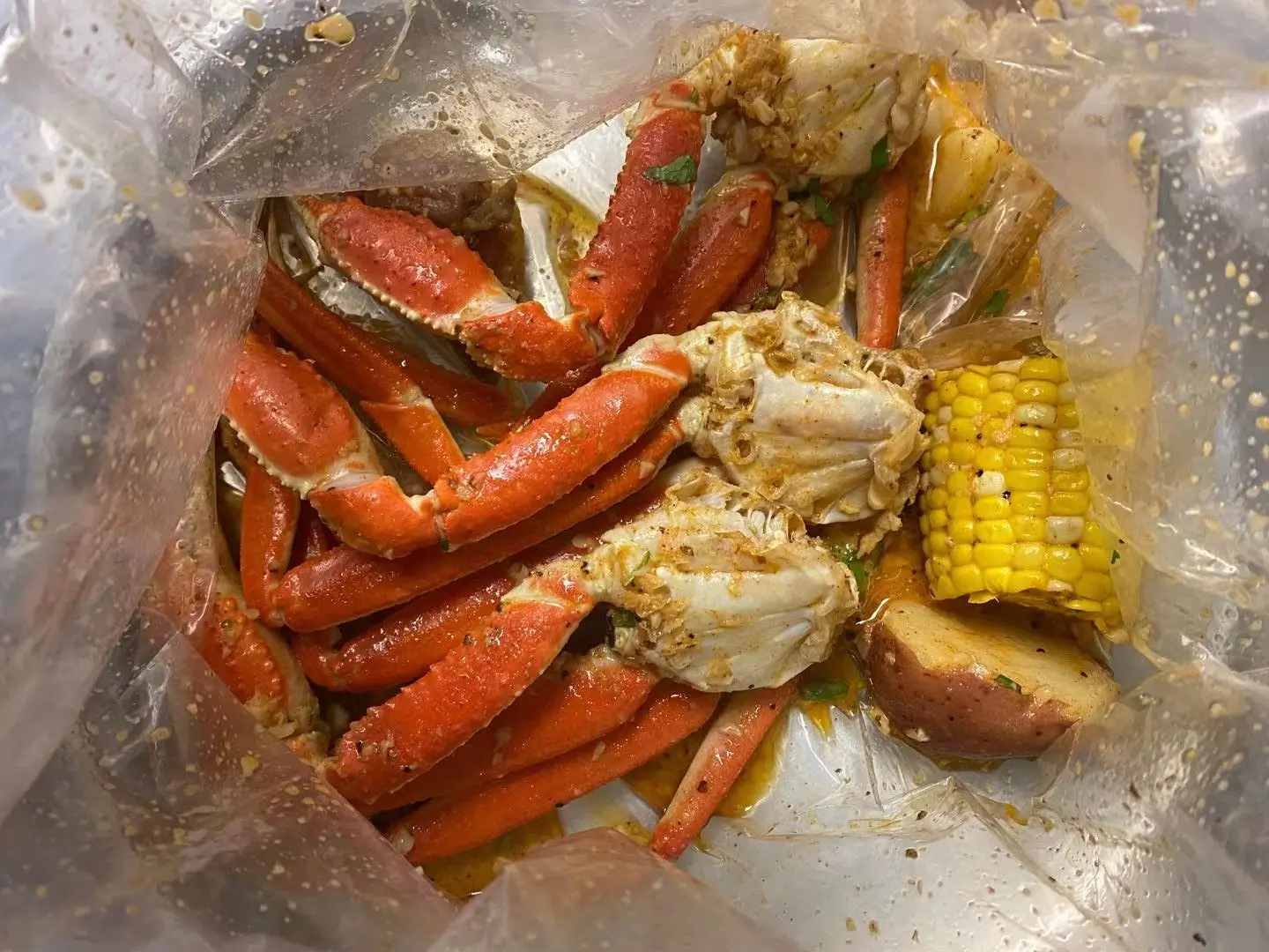 Snow crab legs sprawl across the seafood boil bag like they're lounging at a spa—only here, they're bathing in buttery, garlicky goodness instead.