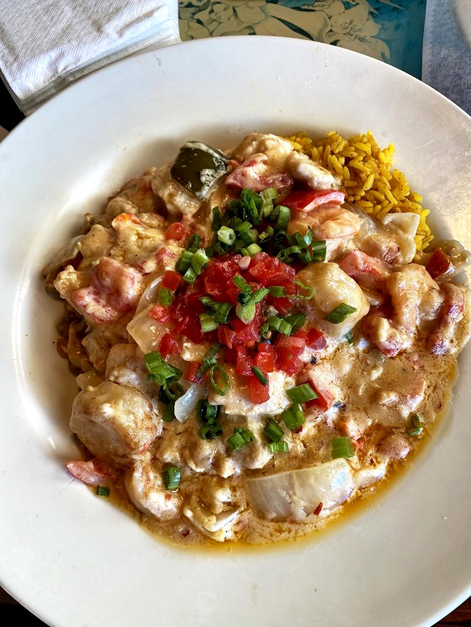 A seafood medley swimming in sauce that demands to be sopped up with bread. The yellow rice underneath isn't just a bed—it's catching every drop of that coastal goodness.