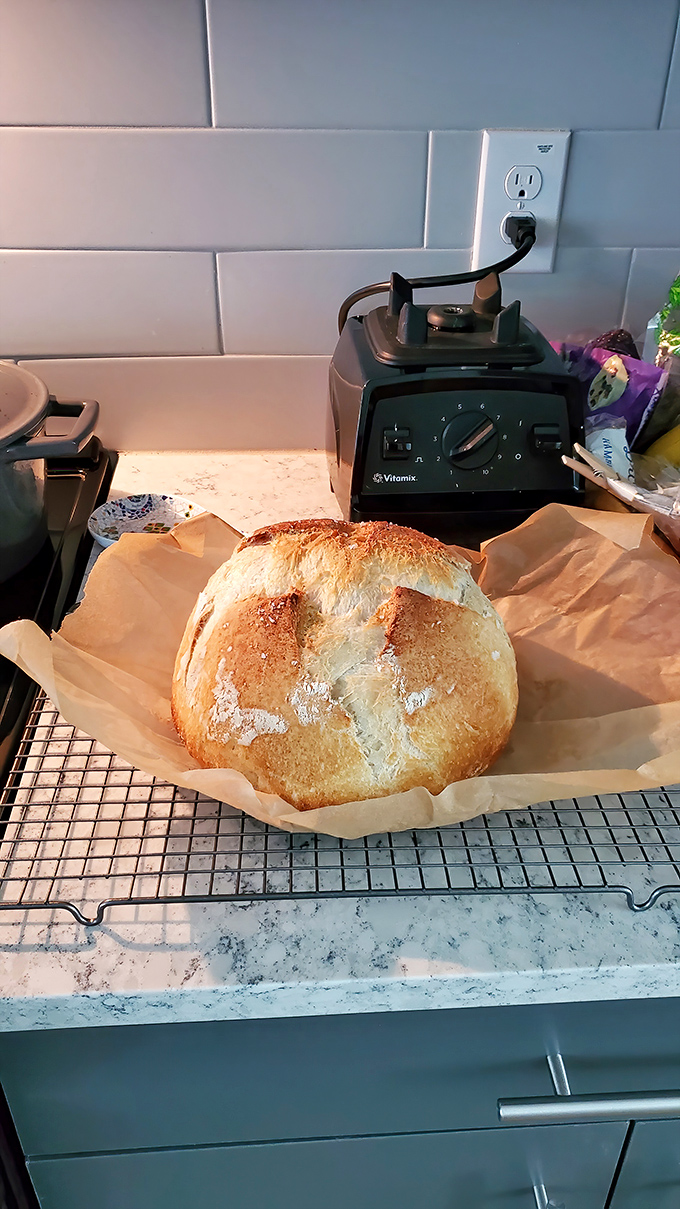 A perfect sourdough boule rests on parchment, its golden crust crackled like nature's pottery, waiting to transform any meal from ordinary to extraordinary.