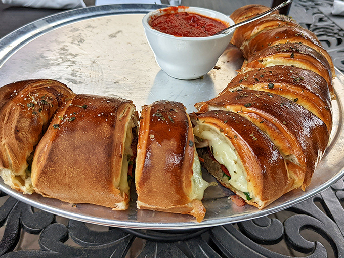 The stromboli arrives like an edible treasure chest, golden-brown and bursting with savory fillings. Dip it in that marinara and prepare for flavor fireworks.