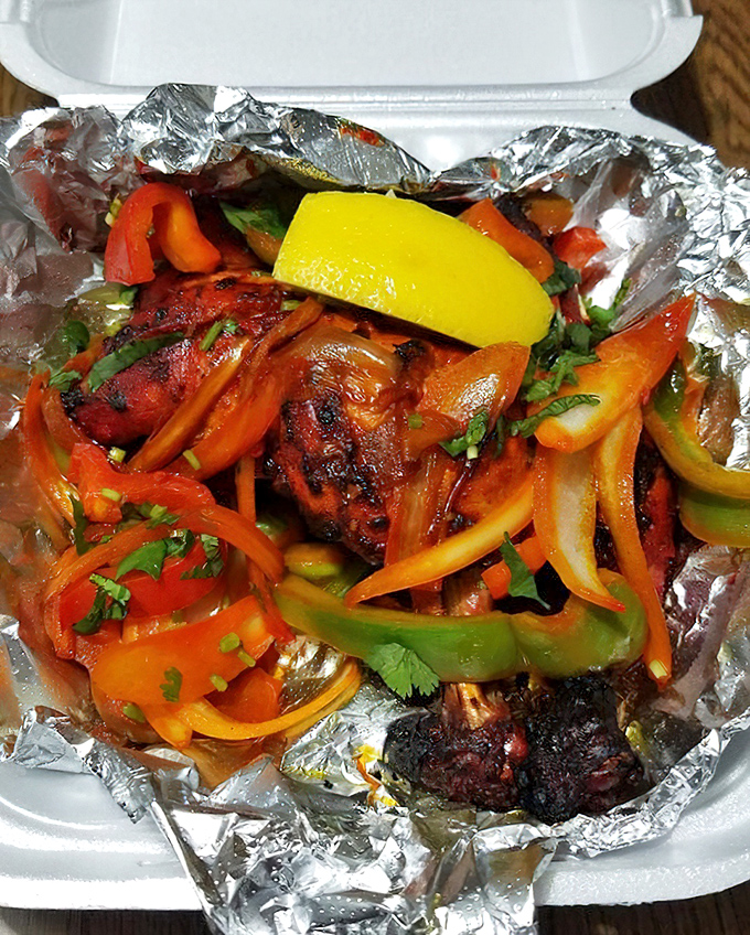 Tandoori chicken nestled among colorful peppers and onions—proof that sometimes the simplest preparations create the most spectacular flavors.