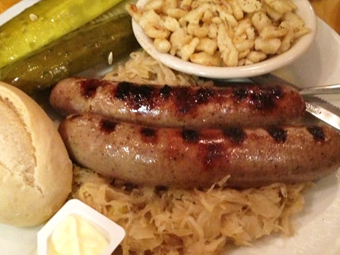 A sausage lounging on a bed of sauerkraut like it owns the place. The pickle stands guard, ensuring maximum flavor security.