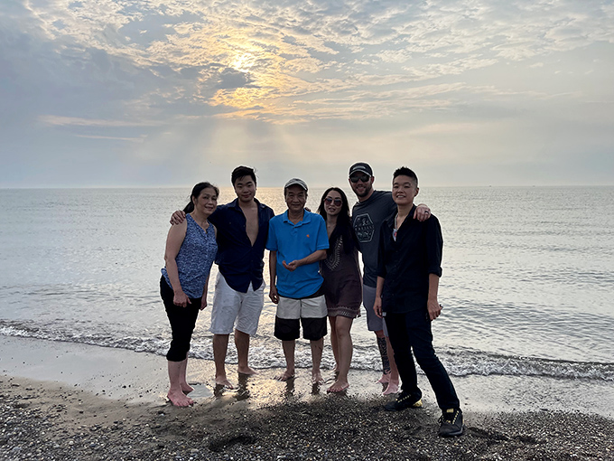 The image shows visitors enjoying a sunset moment at the shoreline, where Lake Erie transforms everyday gatherings into picture-perfect memories.