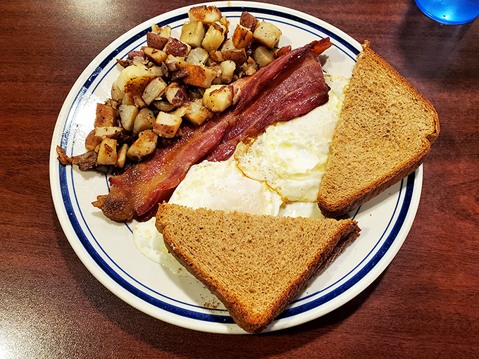 The holy trinity of breakfast: crispy bacon, eggs with sunshine-yellow yolks, and home fries that crackle with each bite. Simple perfection.