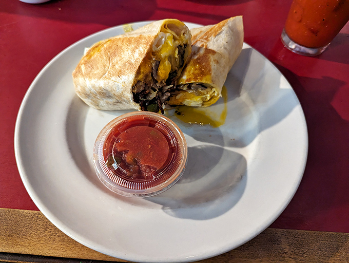 Breakfast burrito perfection: where eggs, cheese, and savory fillings unite in tortilla harmony, with salsa standing by for those who dare.