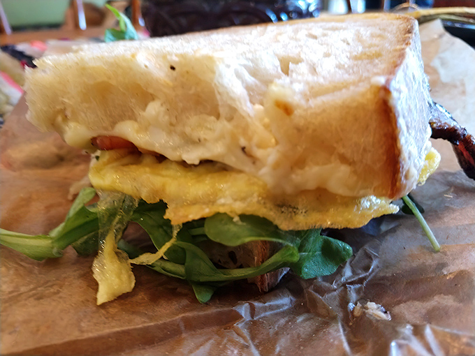 This isn't just breakfast between bread; it's morning salvation with perfectly cooked egg, greens, and bread that deserves its own fan club.