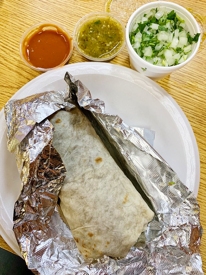 The burrito—wrapped in foil like the precious gift it is—comes with all the proper accessories: red salsa, green salsa, and freshly chopped onion-cilantro confetti.