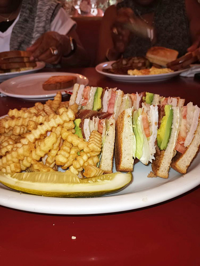 The legendary club sandwich in all its triple-decker glory, with layers that tell a story of culinary craftsmanship and crinkle-cut fries that demand attention.
