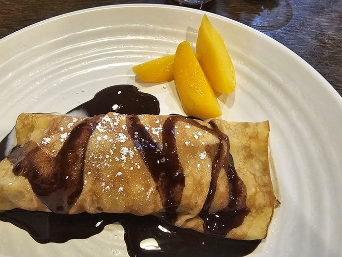 A delicate crepe drizzled with chocolate and paired with fresh peaches. Dessert diplomacy at its finest&mdash;bringing sweet harmony to a seafood-centric meal.