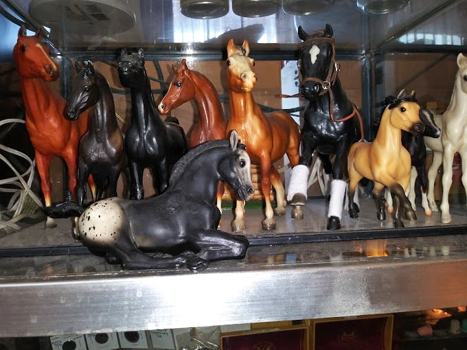 A stable of vintage horse figurines stands frozen in time, each one with the kind of craftsmanship that makes today's mass-produced collectibles hang their tiny heads in shame.