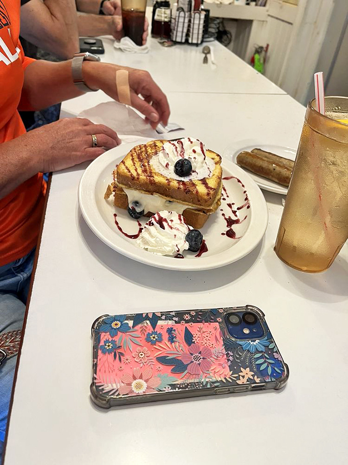 French toast arrives beautifully presented with fresh berries, whipped cream, and artistic drizzles of sweet sauce.