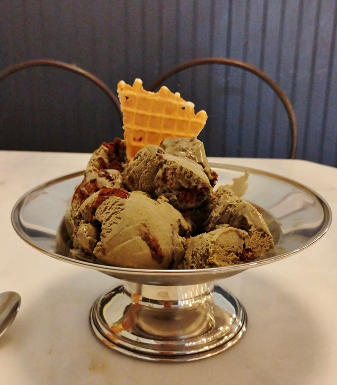 Ice cream served in a proper metal dish with a waffle garnish&mdash;because some traditions deserve the dignity of proper presentation. Elegance in every scoop.