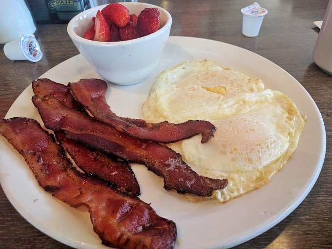 The breakfast trinity: crispy bacon, sunny-side-up eggs, and fresh strawberries&mdash;proof that mornings can actually be wonderful.