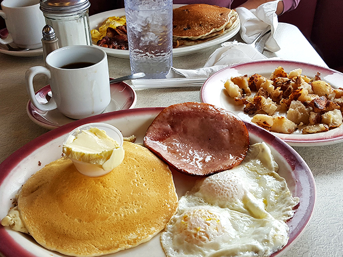 Breakfast platters that could fuel a marathon, featuring the holy trinity of diner perfection: golden pancakes, crispy bacon, and sunny-side-up eggs.