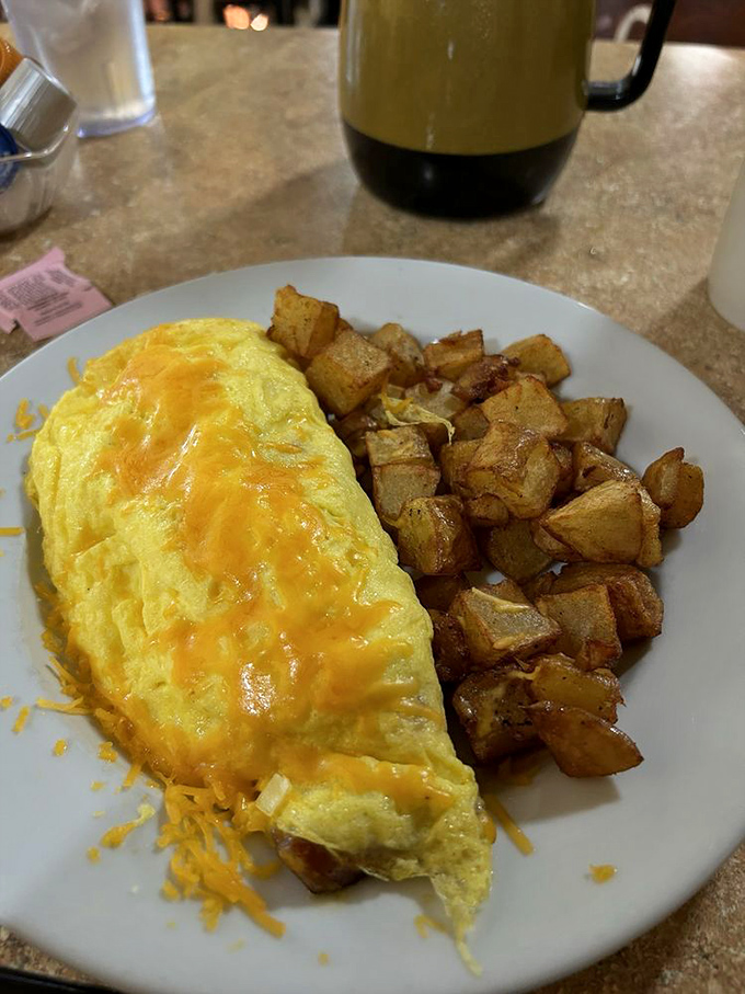 This omelet doesn't just sit on the plate—it commands attention with its golden exterior and generous filling. Home fries never had a better companion.