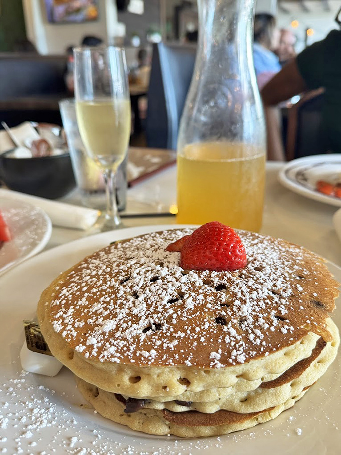 These pancakes aren't just breakfast, they're an event. Dusted with powdered sugar and topped with a strawberry sentinel standing guard.