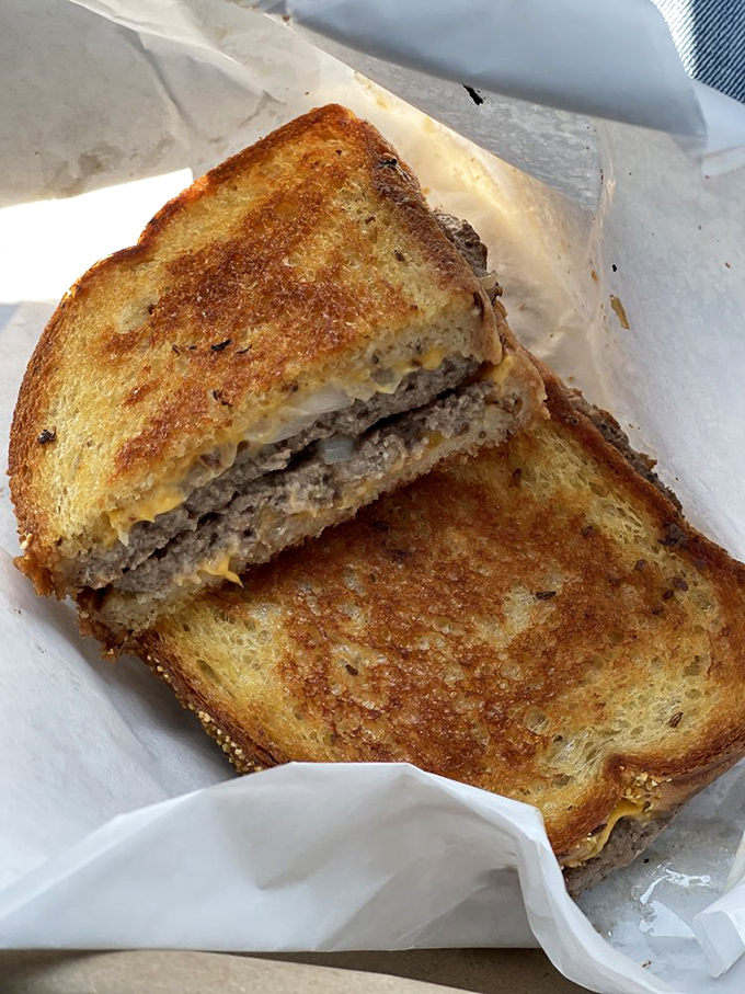 The patty melt reveals its cross-section glory - beef and cheese fused between perfectly griddled bread in a symphony of comfort.