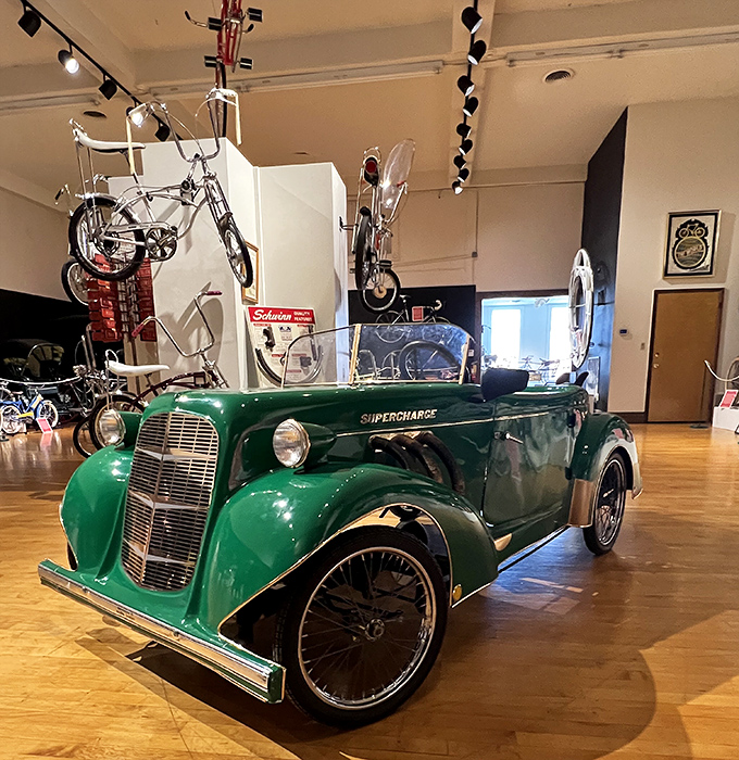 The green "Supercharge" vehicle demonstrates how bicycle technology influenced early automotive design&mdash;wheels before horsepower was even a concept!