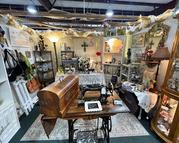 A perfectly staged vignette featuring an antique sewing machine surrounded by lace, figurines, and nostalgia. Someone's grandmother would approve of this display.