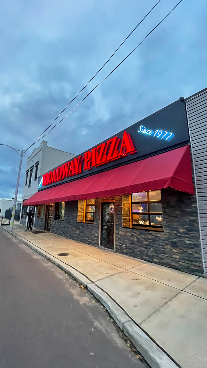 The evening glow of Broadway Pizza's neon sign calls to night owls. Since 1977, this red-awning wonder has been Memphis's late-night pizza salvation.