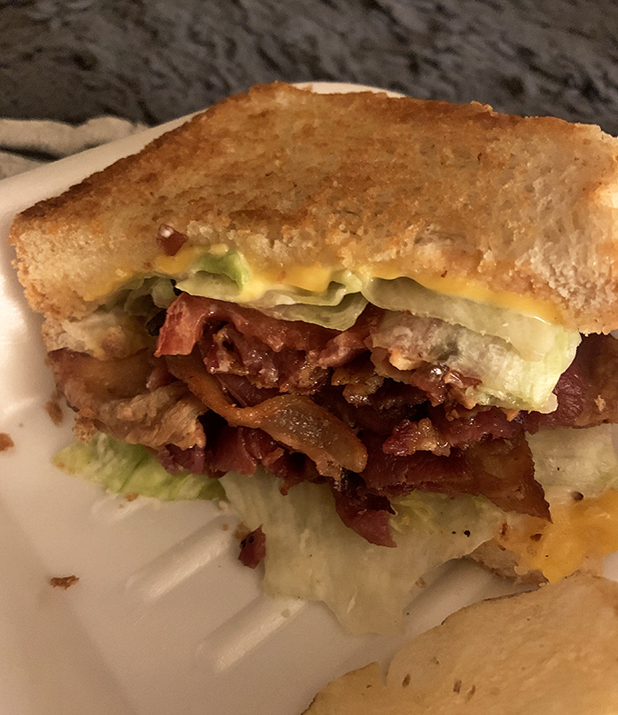 This isn't just a sandwich; it's architecture. Layers of bacon, lettuce and cheese creating the skyscraper of comfort food your stomach deserves.