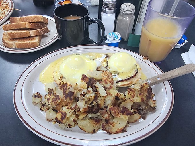 Eggs Benedict executed with textbook precision. The hollandaise sauce gleams like morning sunshine over a landscape of potatoes.