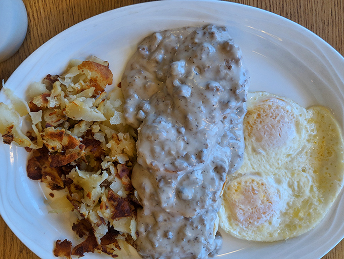 Biscuits smothered in creamy sausage gravy alongside perfectly crisp home fries. A plate that says "Go back to bed after this" in the most delicious way possible.