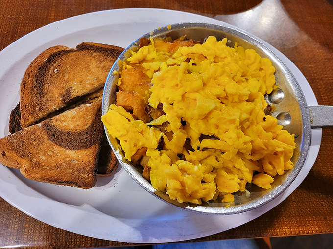A skillet where eggs, potatoes, and cheese have formed a delicious democracy. That English muffin is just waiting for its diplomatic mission.