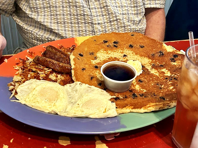That pancake is staging a hostile takeover of the plate while eggs and bacon serve as delicious accomplices.