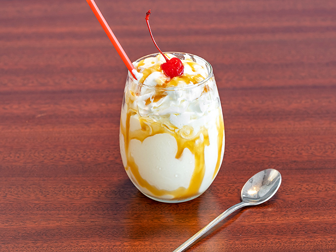 Caramel shake artistry with whipped cream, drizzle, and a cherry on top—dessert disguised as a beverage and nobody's complaining.