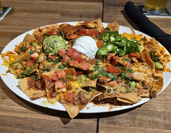 Nachos architecture that defies both gravity and restraint. That guacamole dollop is the emerald crown jewel of this crunchy kingdom.