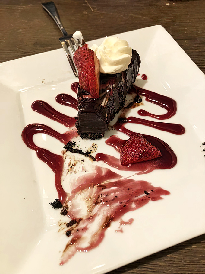 This chocolate torte stands tall like a decadent monument to dessert perfection, crowned with whipped cream and fresh strawberries.