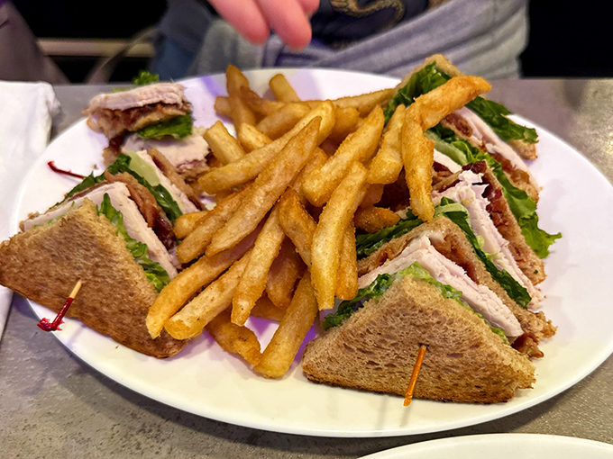 The club sandwich&mdash;that triple-decker marvel where geometry and gastronomy meet, with golden fries standing guard like delicious sentinels.