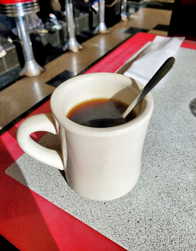 That sturdy white mug isn't just holding coffee—it's cradling liquid motivation in a vessel that's survived more morning rushes than most relationships.