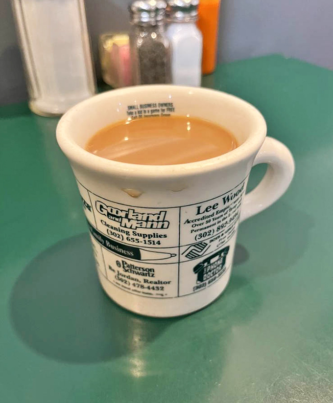 The coffee mug&mdash;advertising local businesses and filled with that honest diner brew that doesn't need a fancy origin story to wake you up right.