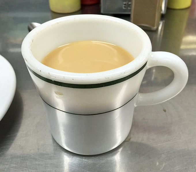 Coffee served in a mug with character marks—each chip and stain a testament to countless conversations and early morning salvation.