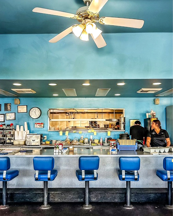 The counter seats&mdash;where solo diners become regulars and the coffee flows like conversation. Blue vinyl never looked so inviting.