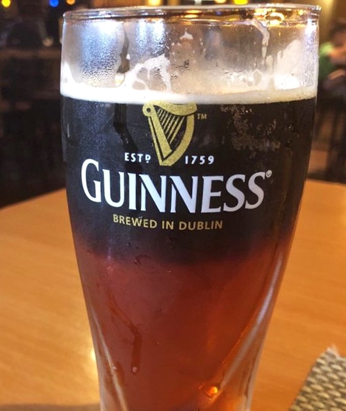 A perfectly poured Guinness waiting patiently while you debate ordering just one more round of wings.